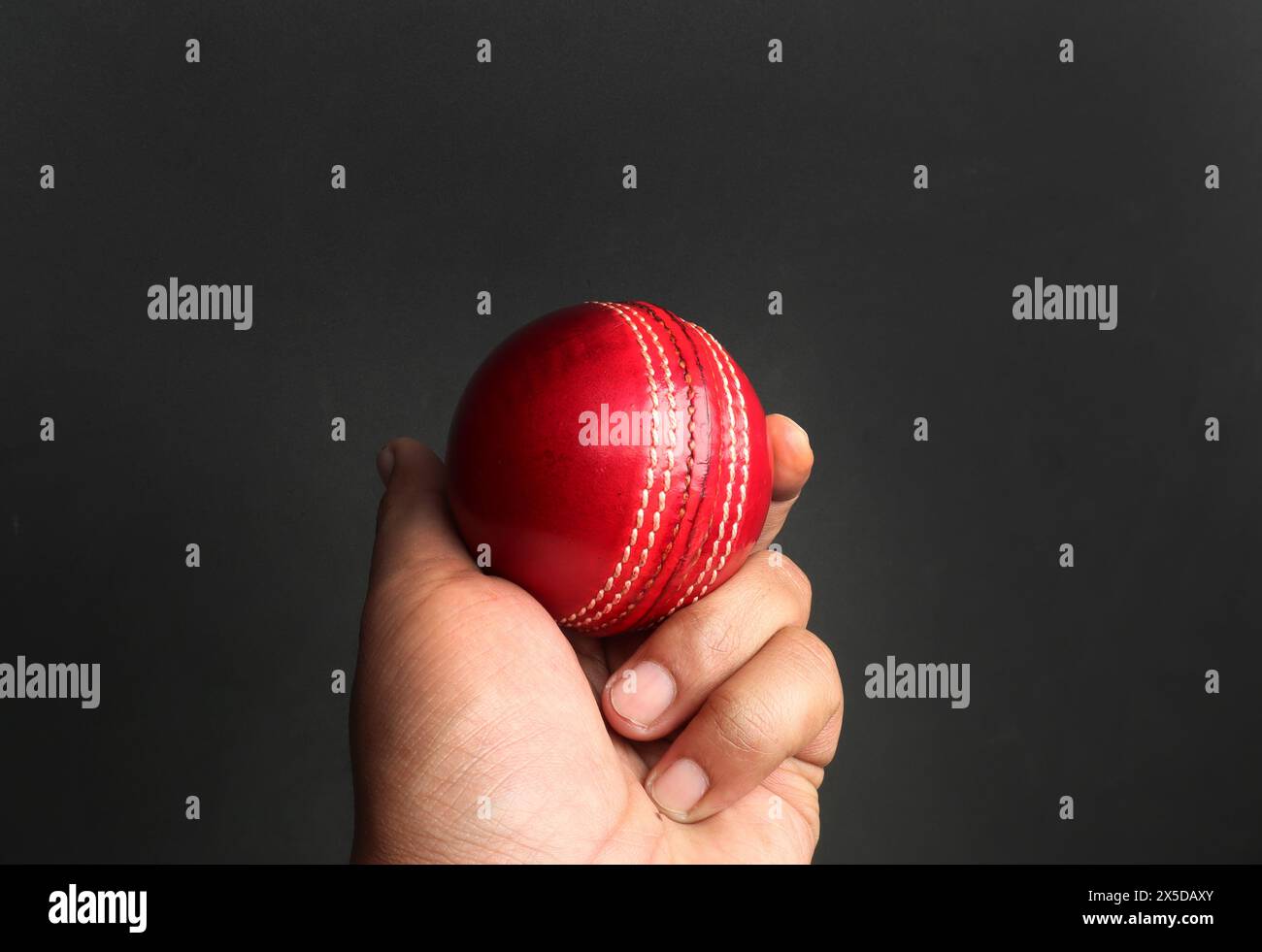 red cricket leather ball in bowler's hand on the dark background Stock ...