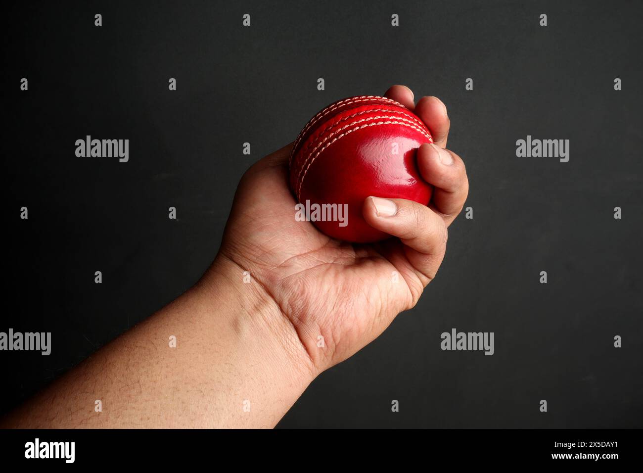 red cricket leather ball in bowler's hand on the dark background Stock ...
