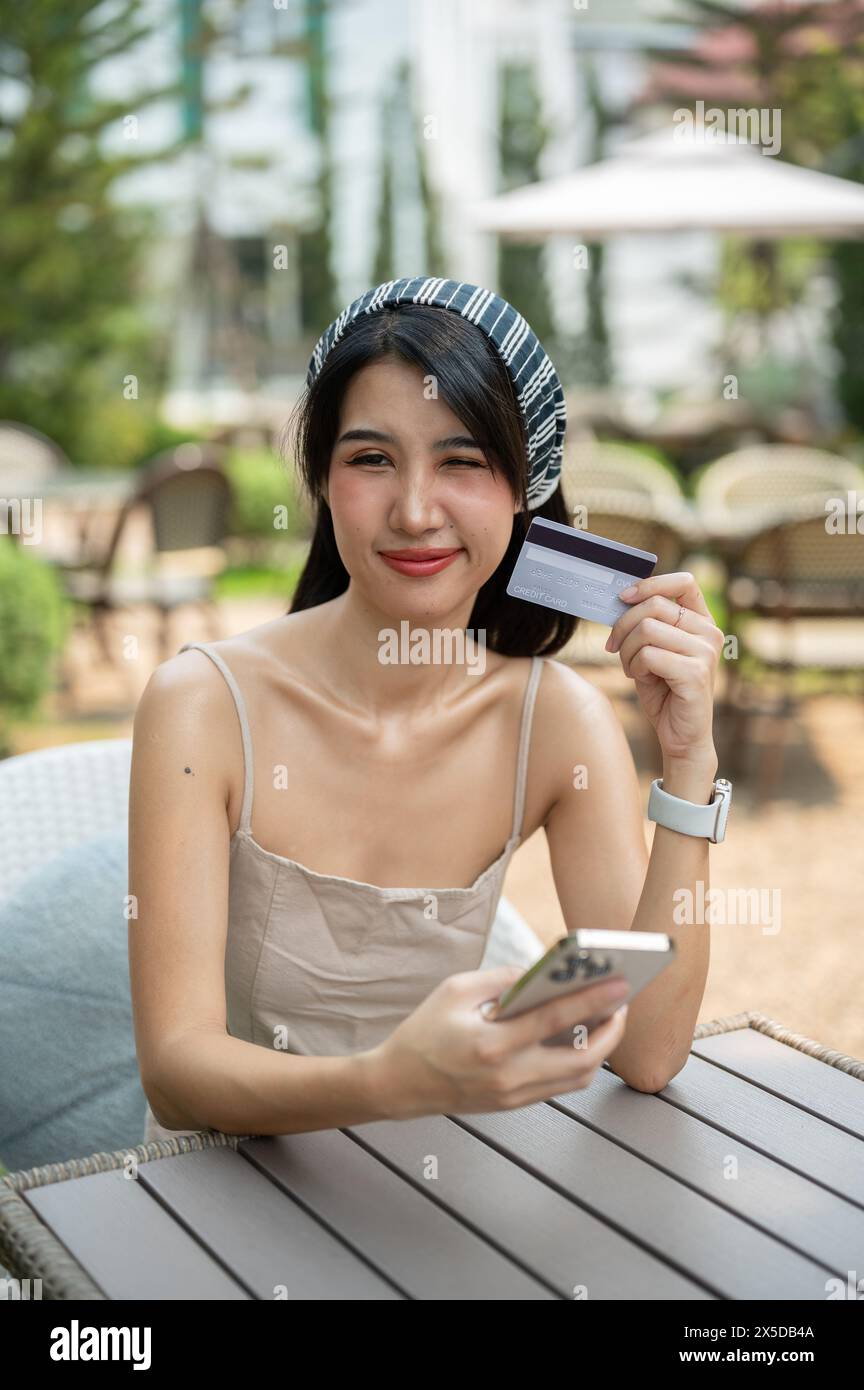 An attractive, smiling Asian woman in a cute minimal dress sits at a ...
