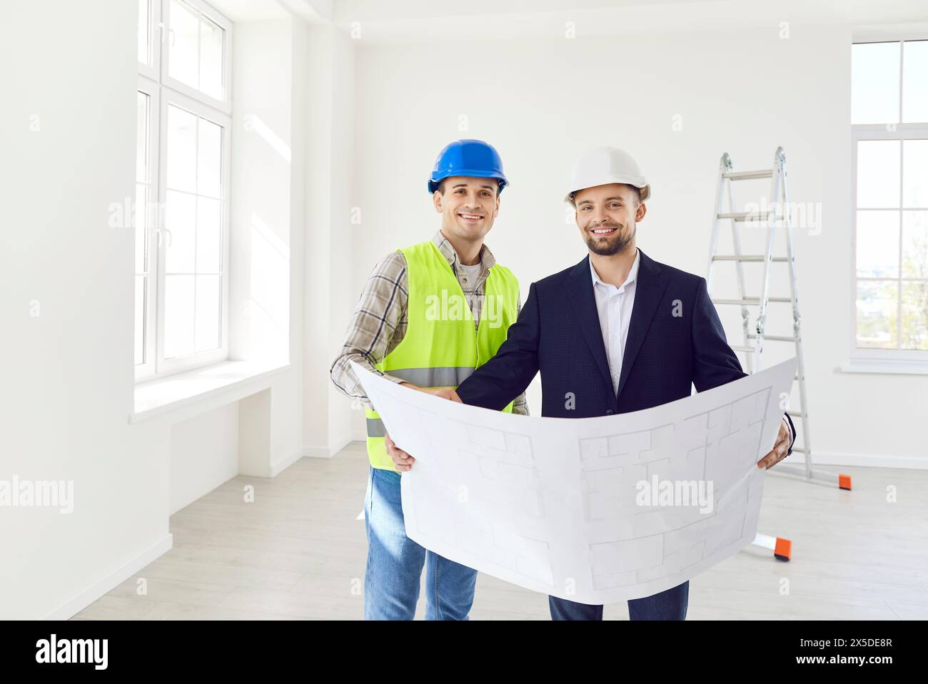 Male builder and engineer happy holding project paper plan for ...