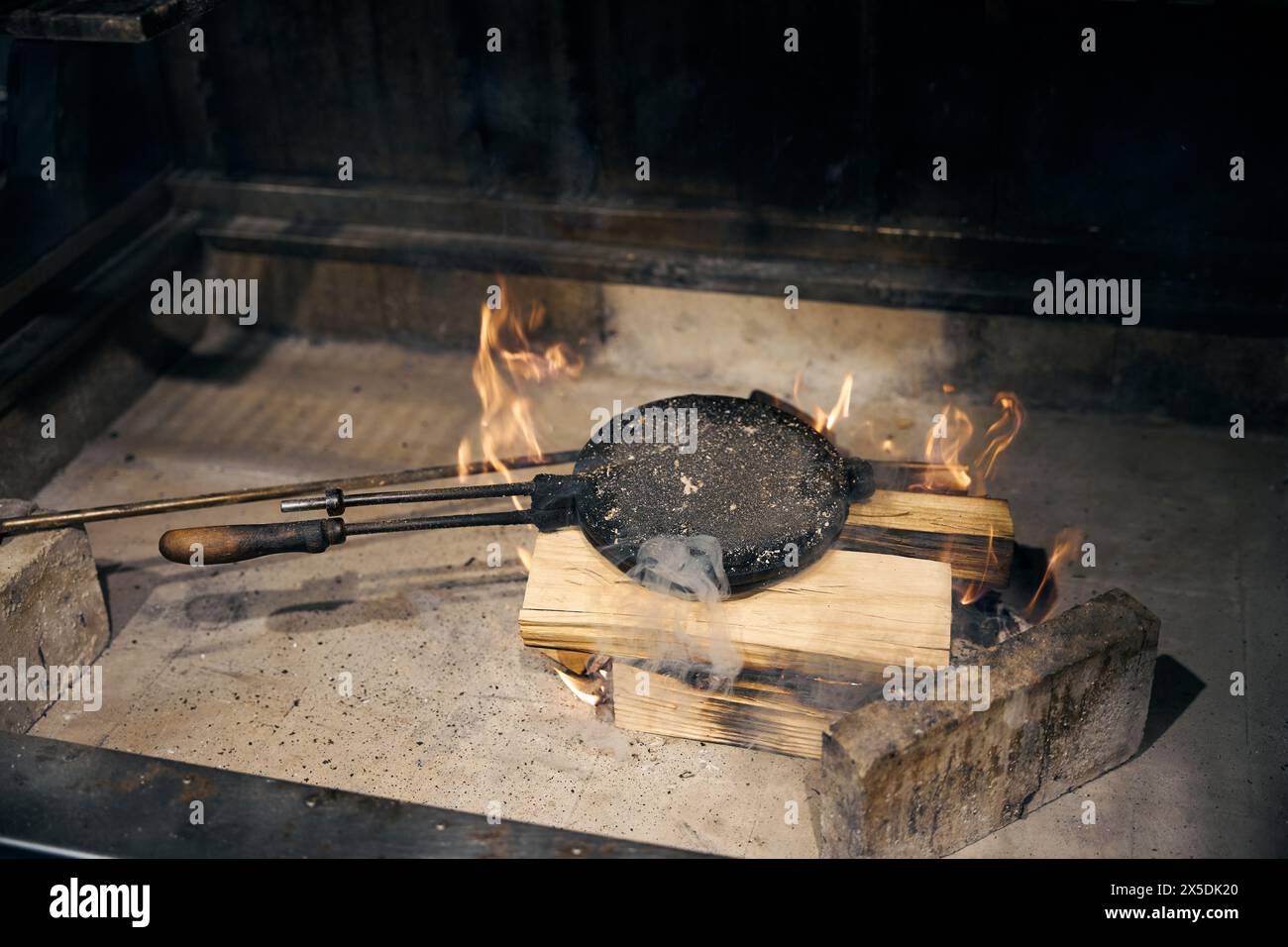 Pancake maker over woods in burning open stove before food cooking in ...