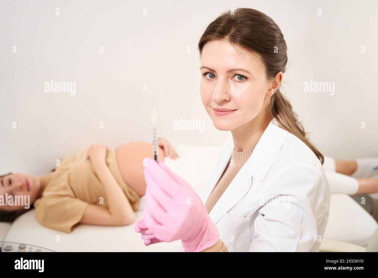 Gynecologist with syringe looking at camera before injection of ...