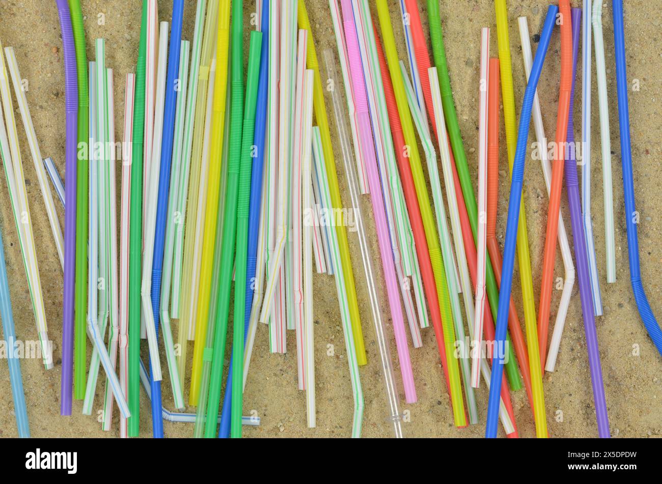 Colorful plastic straws, waste on a beach after summer festival or ...