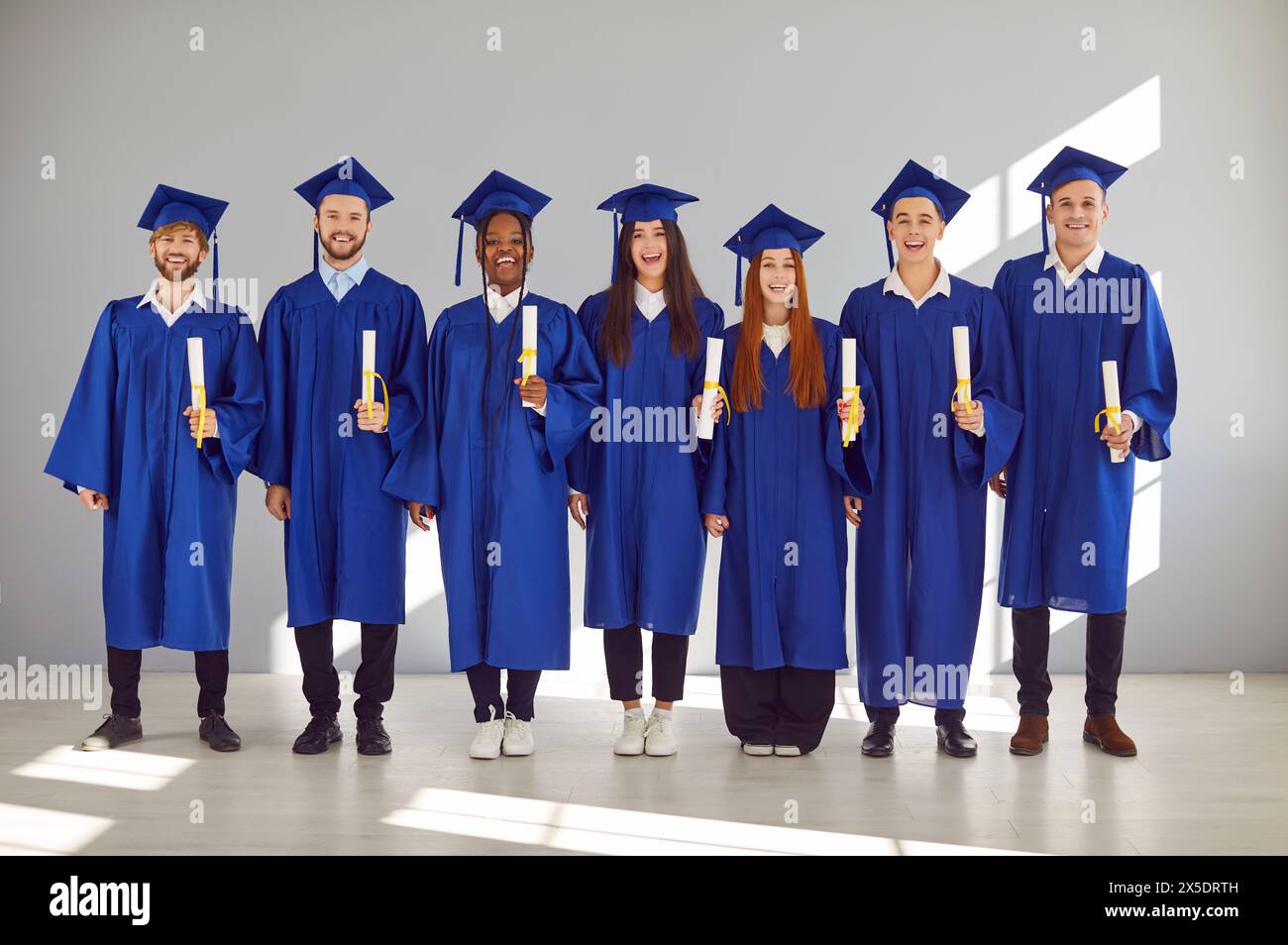 Group of happy diverse students in blue caps and gowns celebrating ...