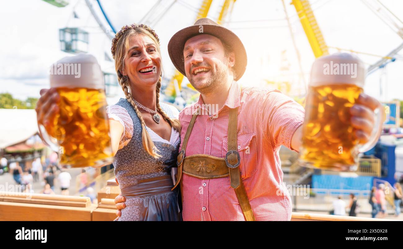 Bavarian couple in traditional Bavarian attire cheerfully toasting with ...