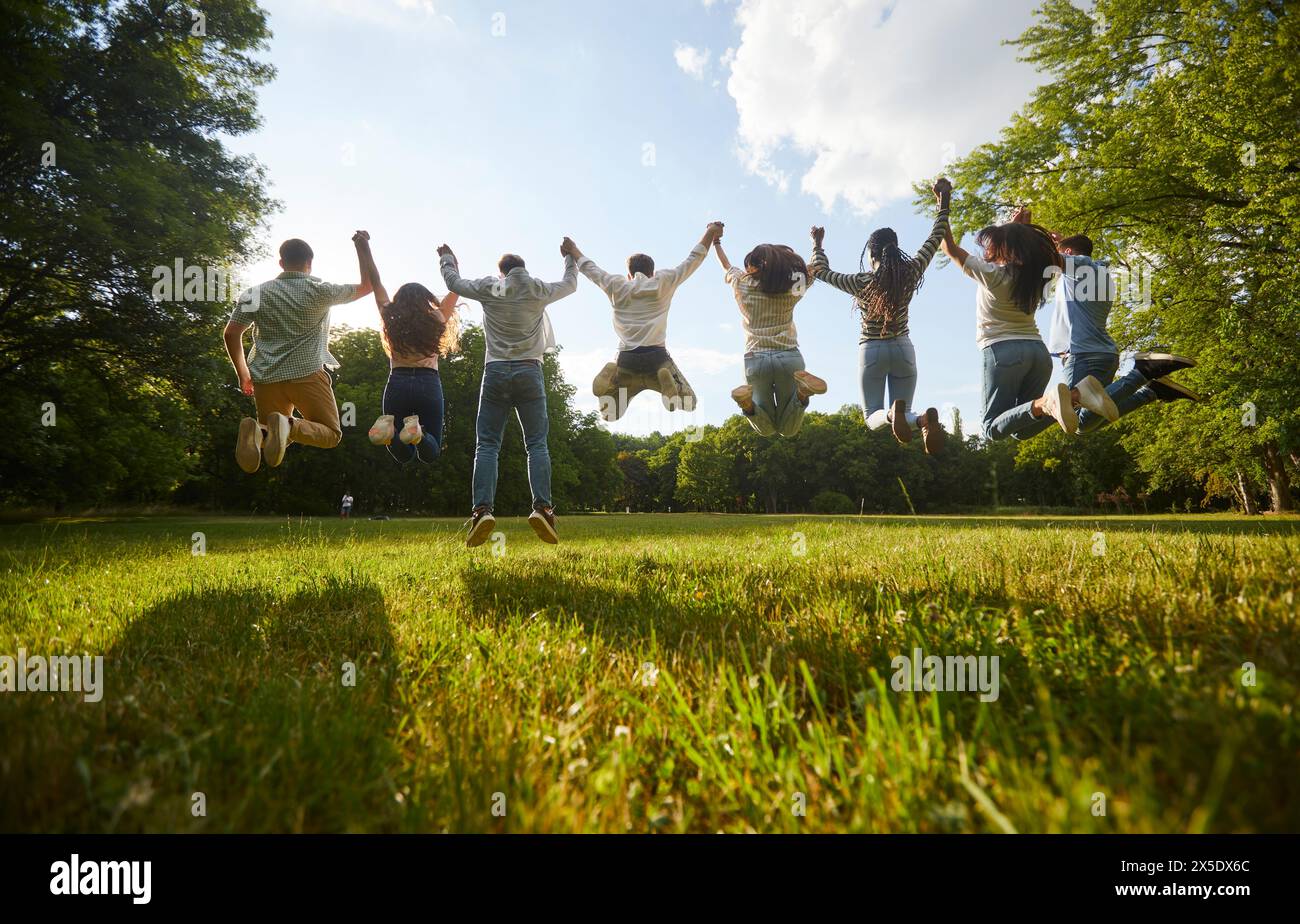 Group of friends jumping in air with raised hands while having fun in ...