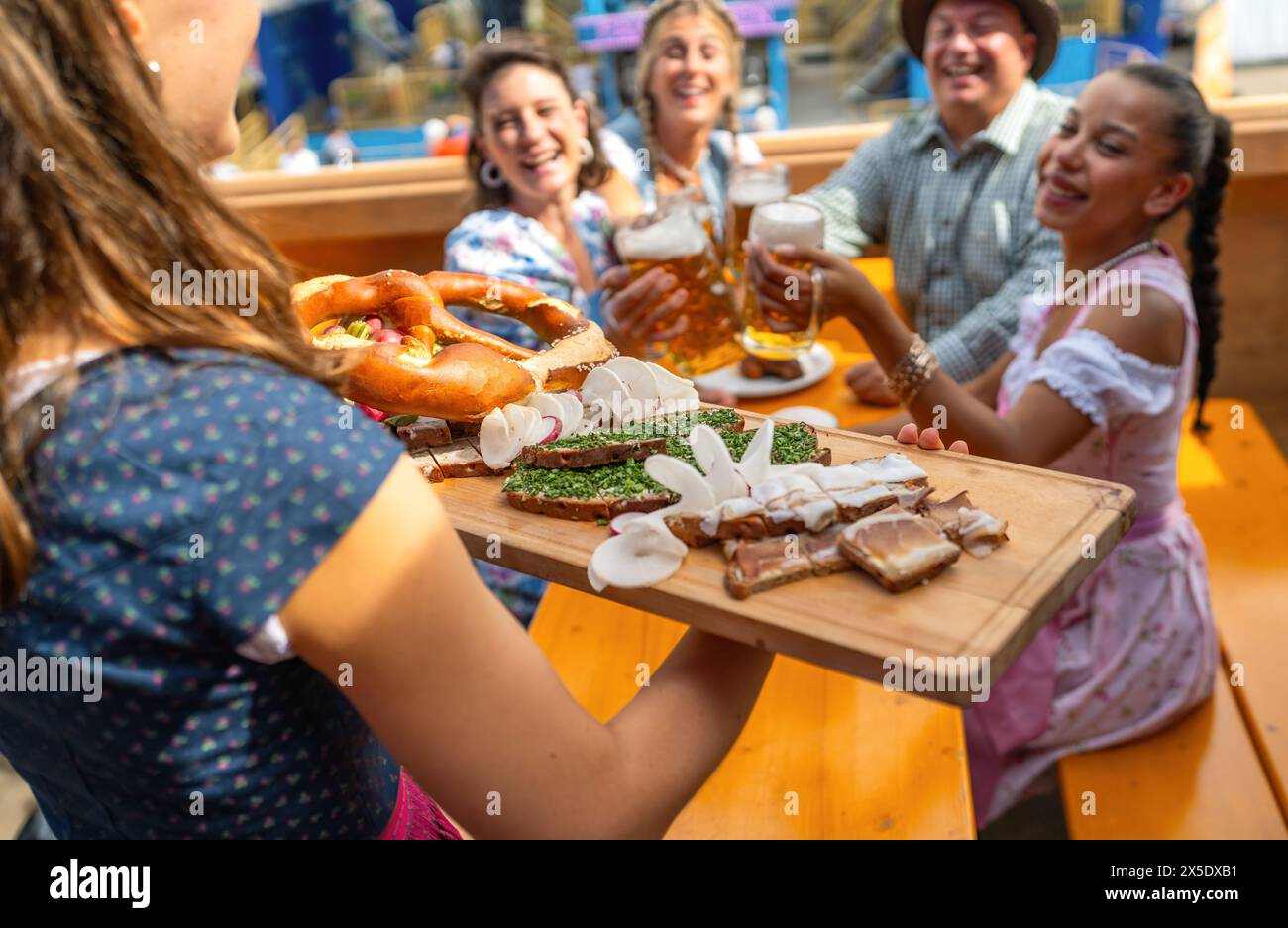 Waitress serving a wooden platter of traditional German food to a group ...
