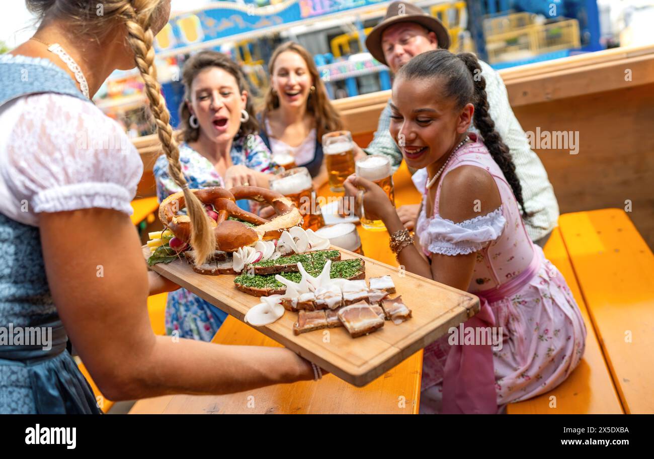 Waitress in traditional attire serving a platter of German food to a ...
