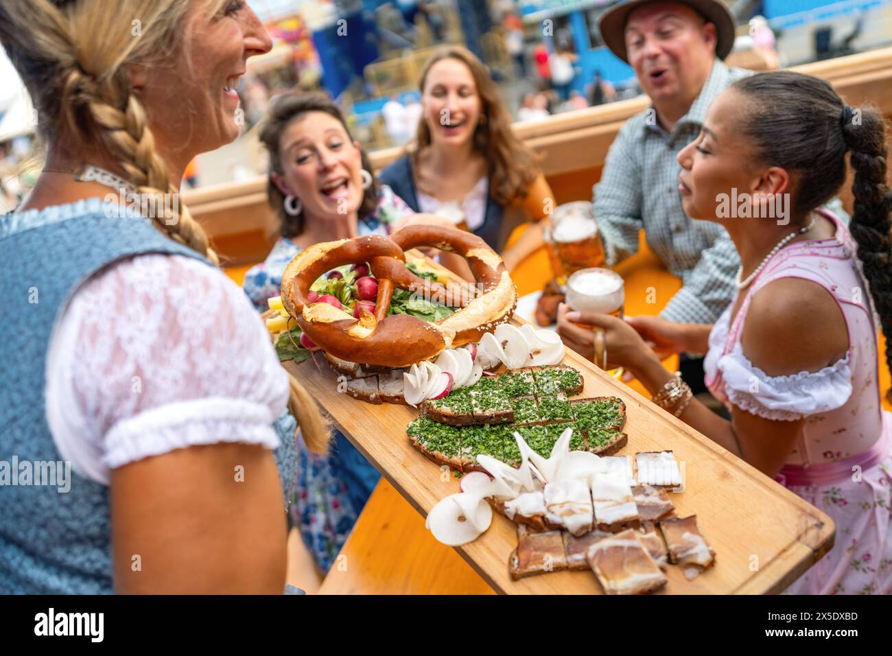 Joyful waitress serving traditional German food on a wooden platter to ...