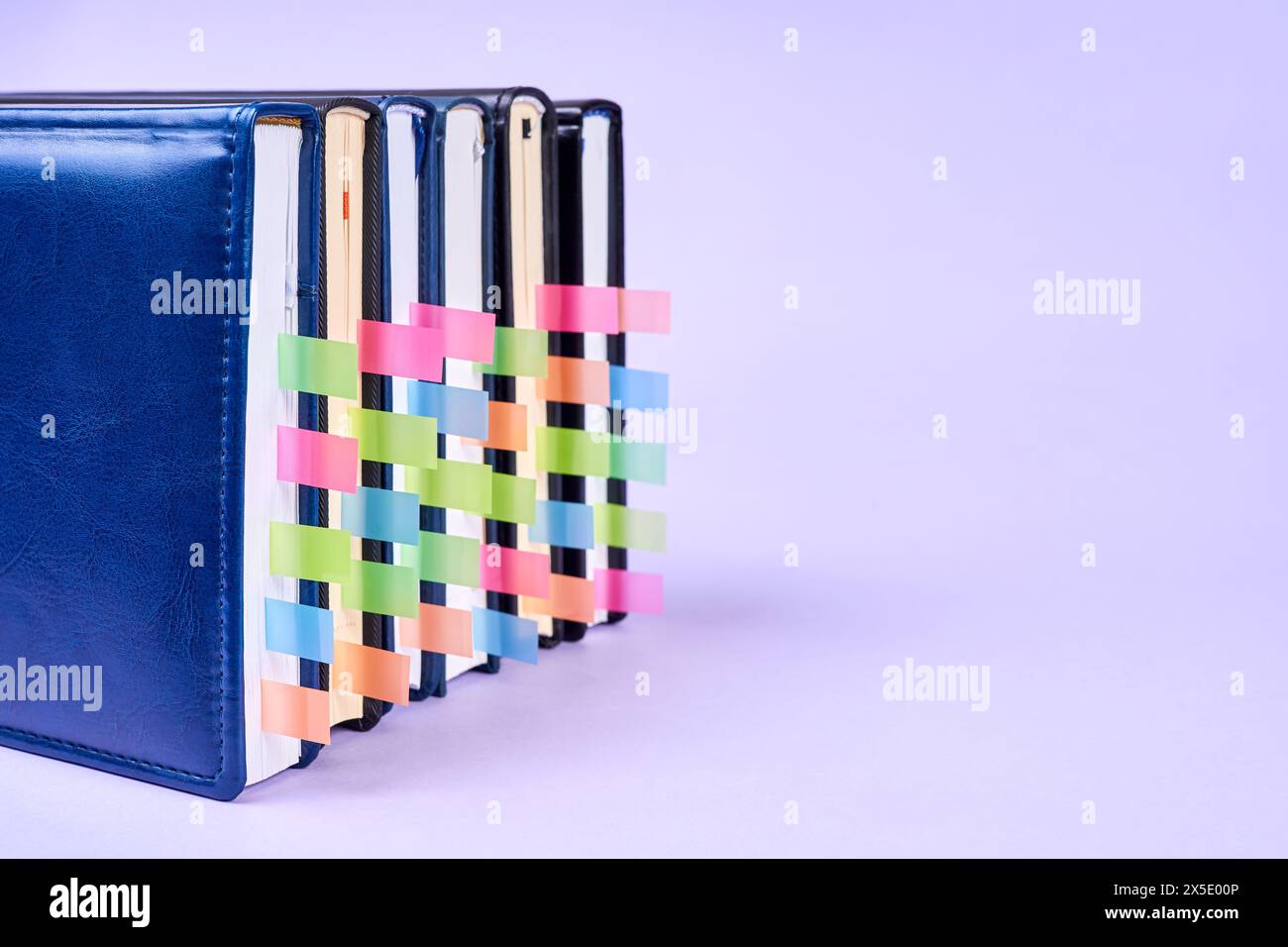 A stack of office notepads with colorful sticky page markers sandwiched ...