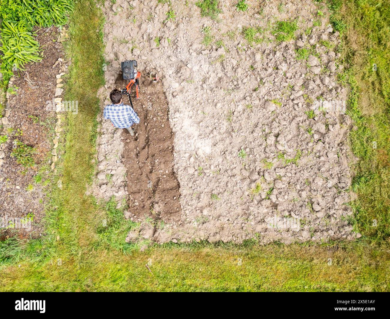 Young farmer man is cultivating the field with machine. Aerial drone ...