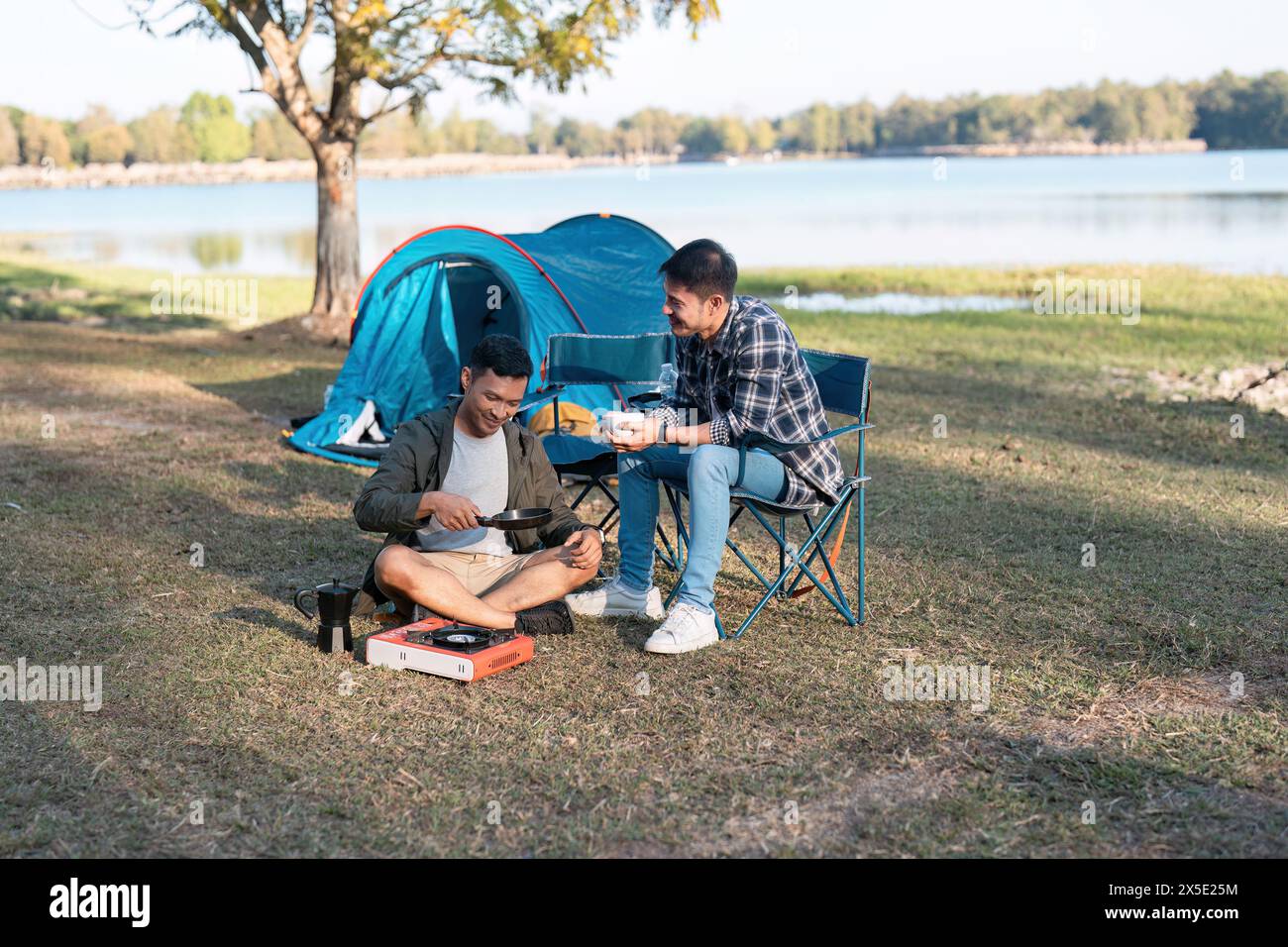 couple gay lgbt sitting in camp cooking and near river in mountains ...