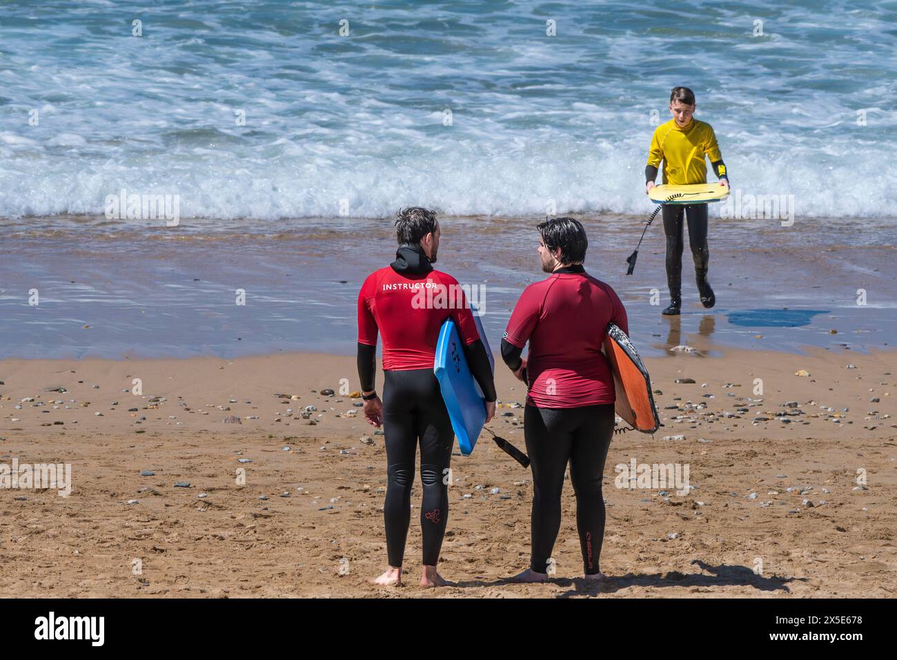A surfing instructor with novices during a body boogie boarding lesson ...