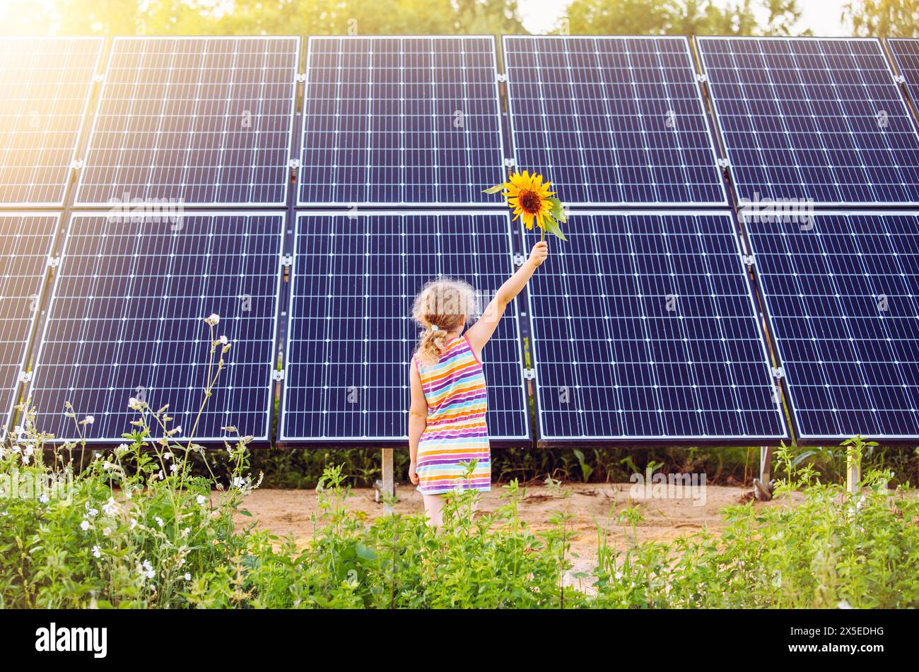 Young 6 year old blonde girl child standing in front of small solar ...
