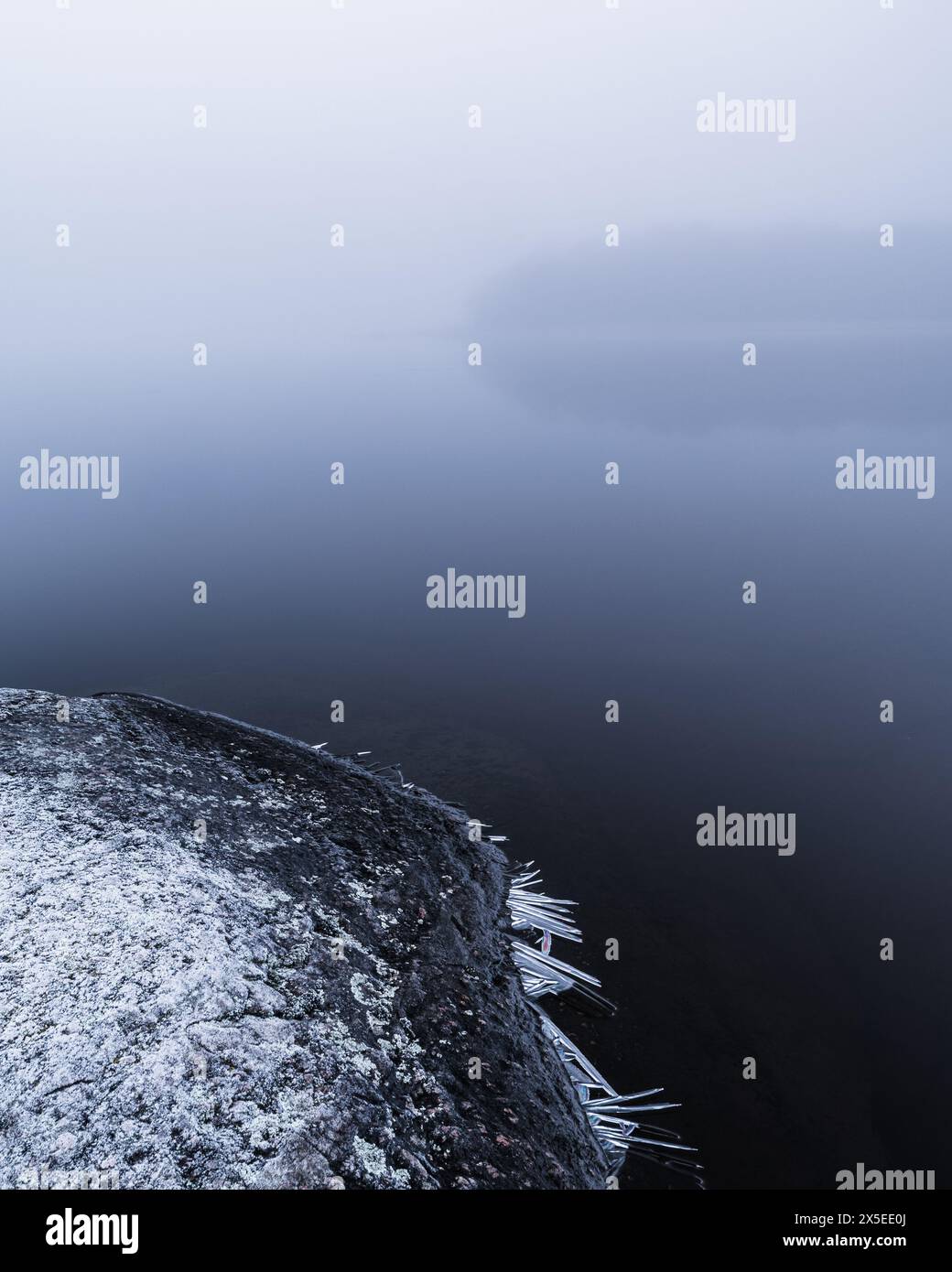 A peaceful lakeside scene unfolds with a frosted rock gently extending ...