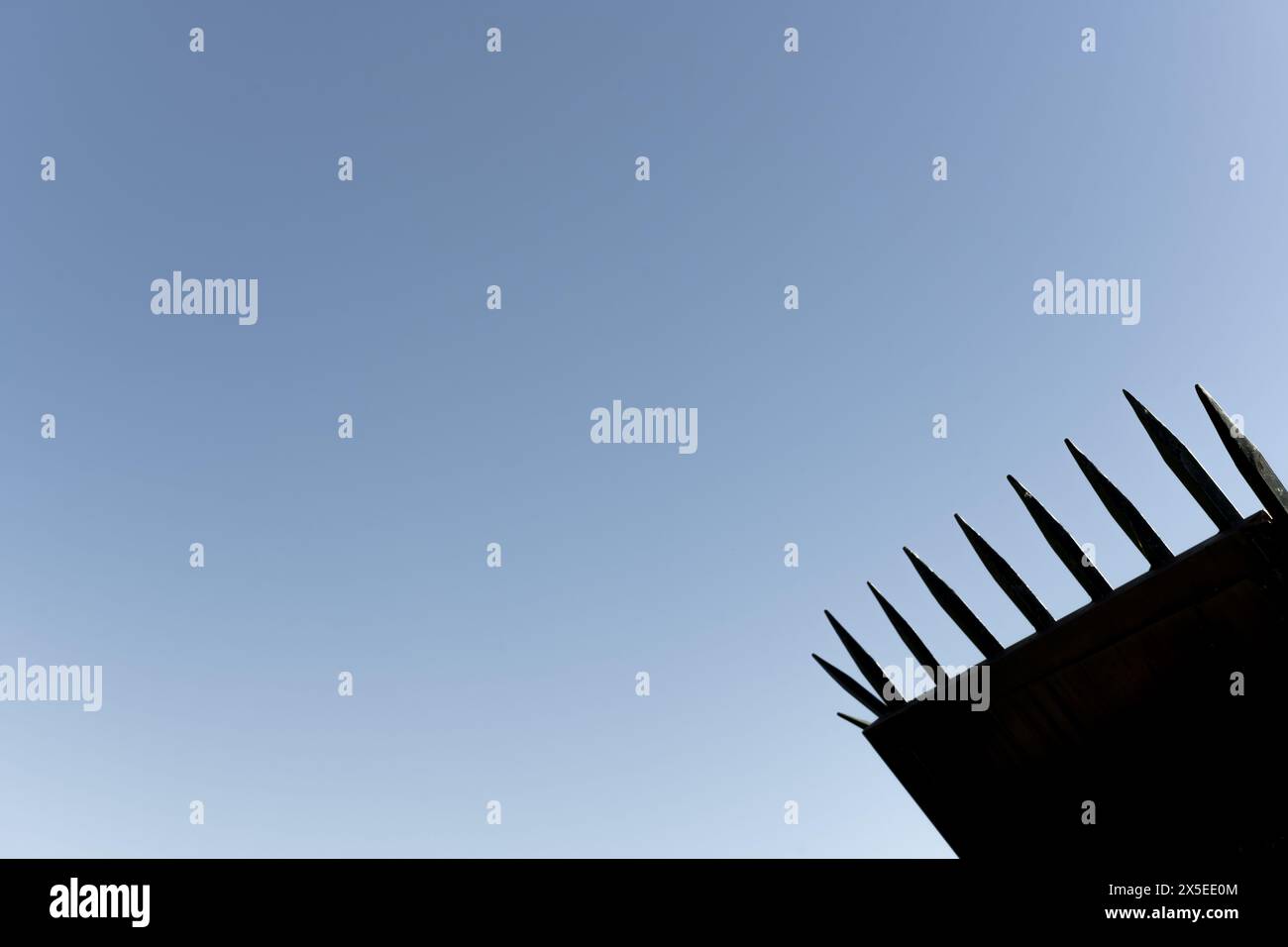 Backlit spikes on top of a perimeter fence Stock Photo - Alamy