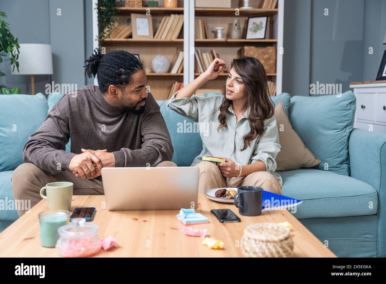 Positive hipster couple having fun while working together remotely at ...