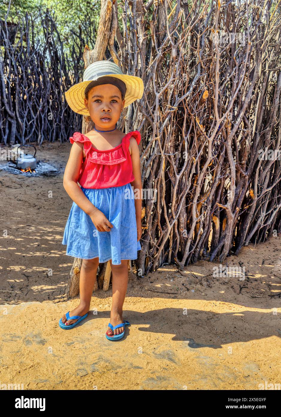 African village, cute little girl with a straw hat, tea on the open ...