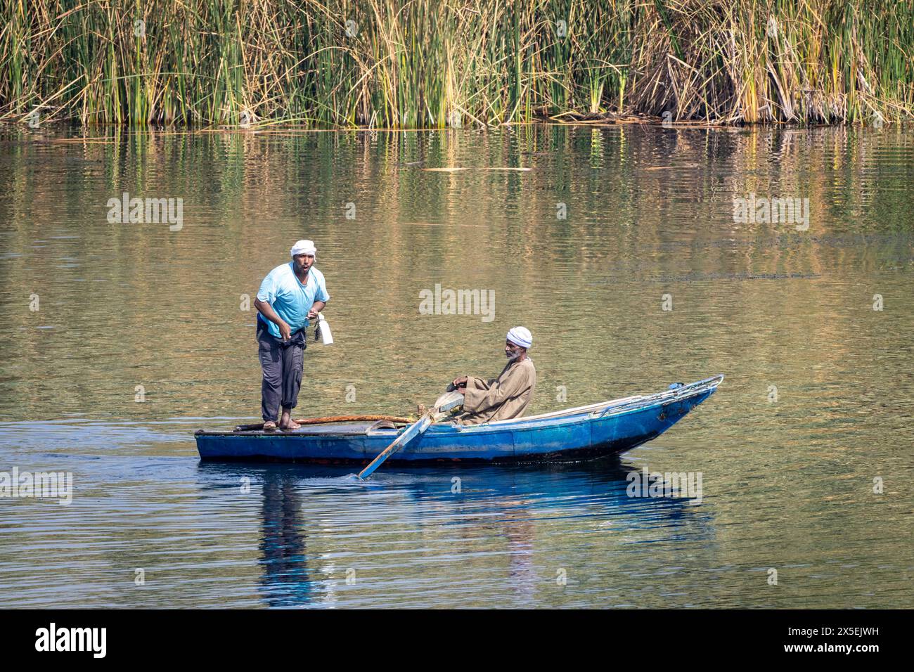 Local Egyptians fishing on the Nile River in Egypt. Small row boats are ...