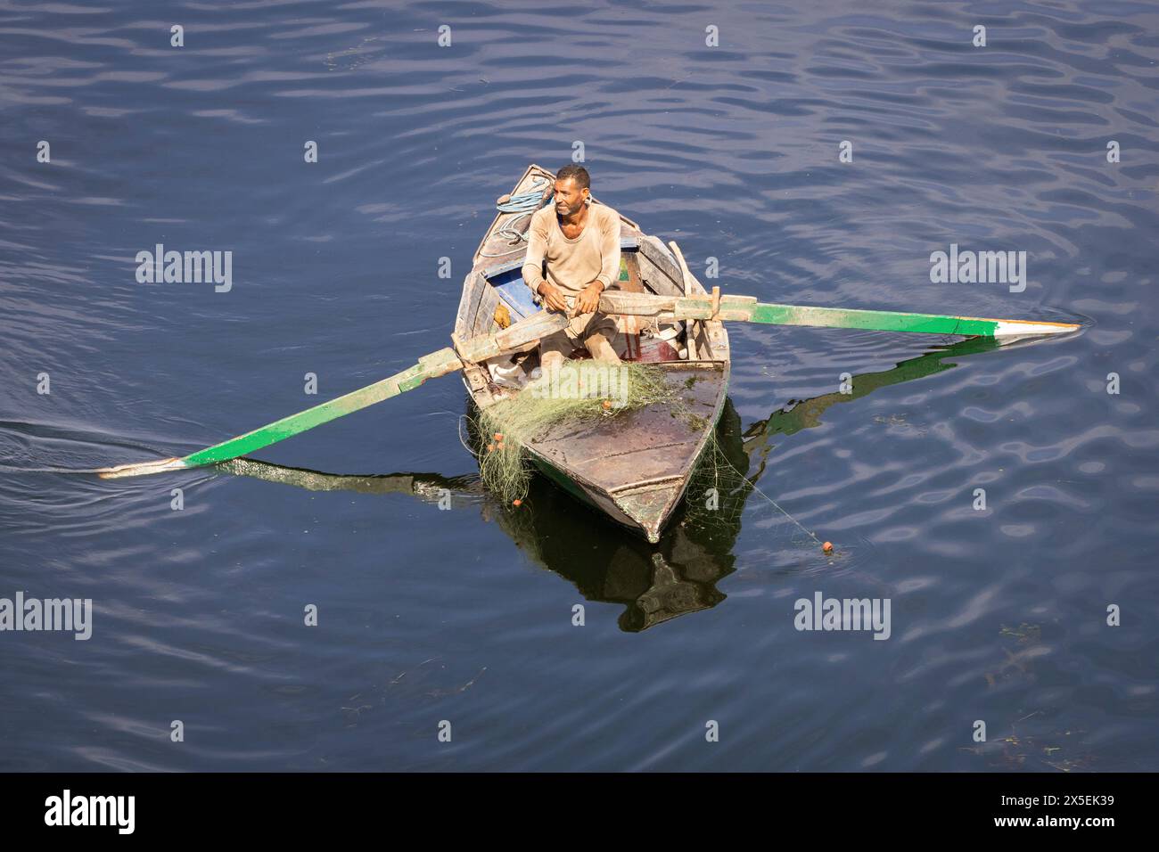 Local Egyptian fishing on the Nile River in Egypt. Small row boats are ...