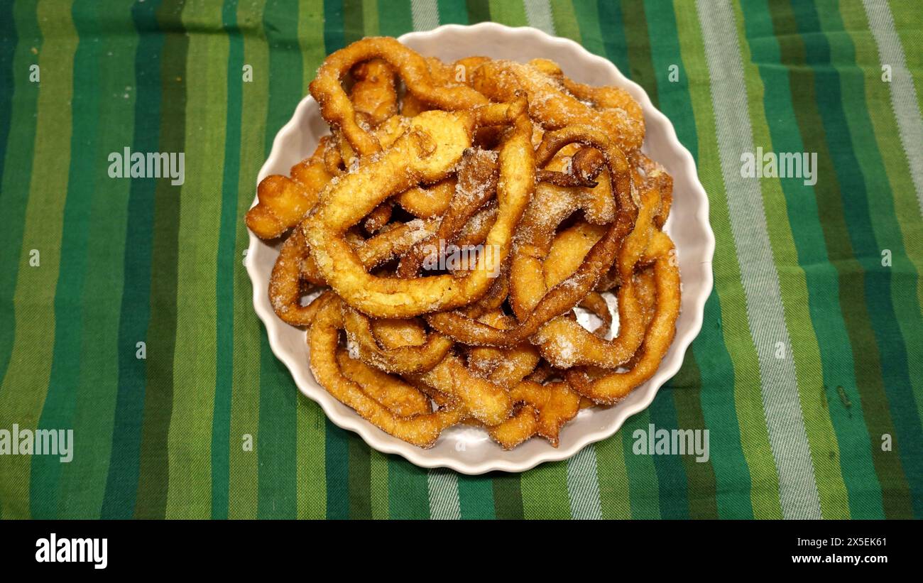 A tray of fried dough snakes with sugar ready to eat. Traditional ...
