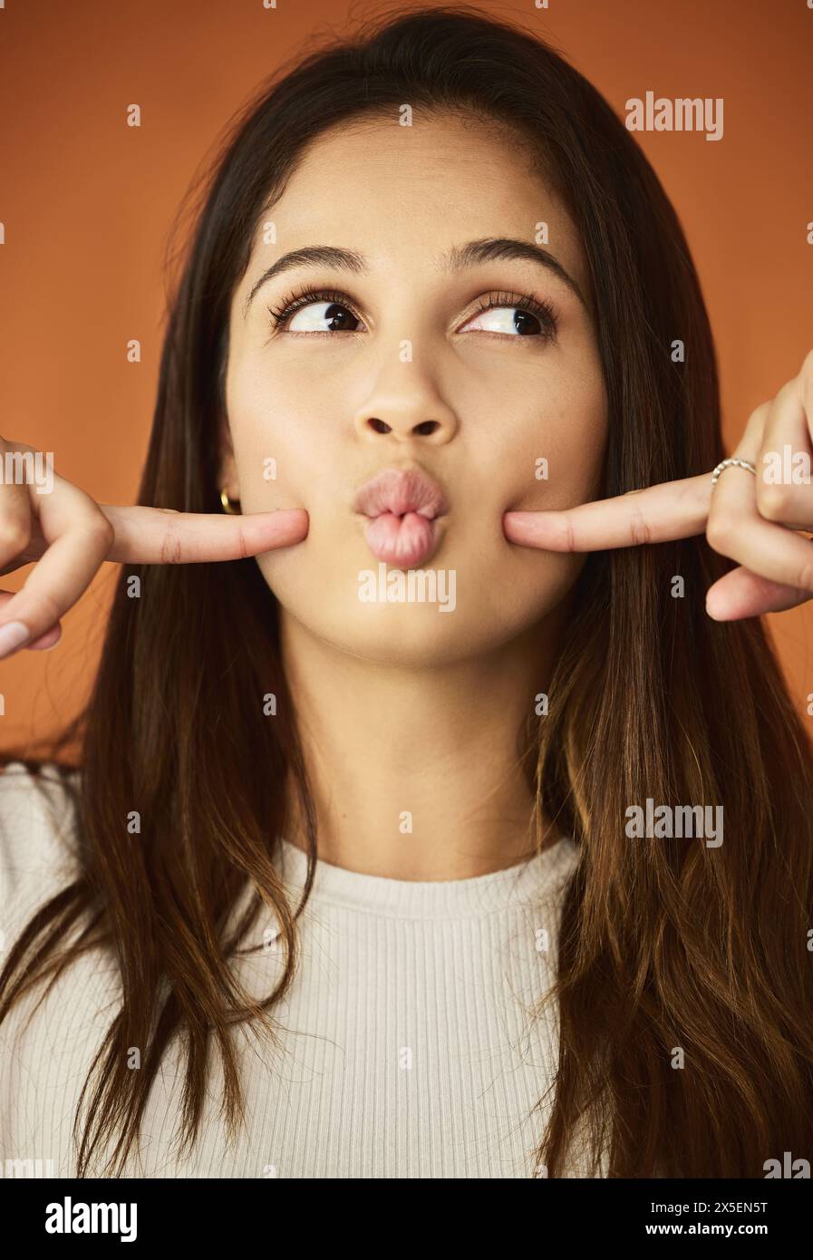 Funny face, fingers and woman in studio for humor, comedy or cheeks ...