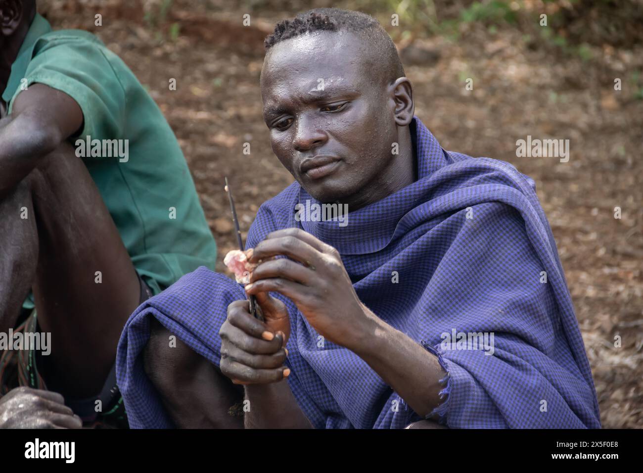 Mursi Tribe (Ethiopia) gathered around fire place, preparing, sharing ...