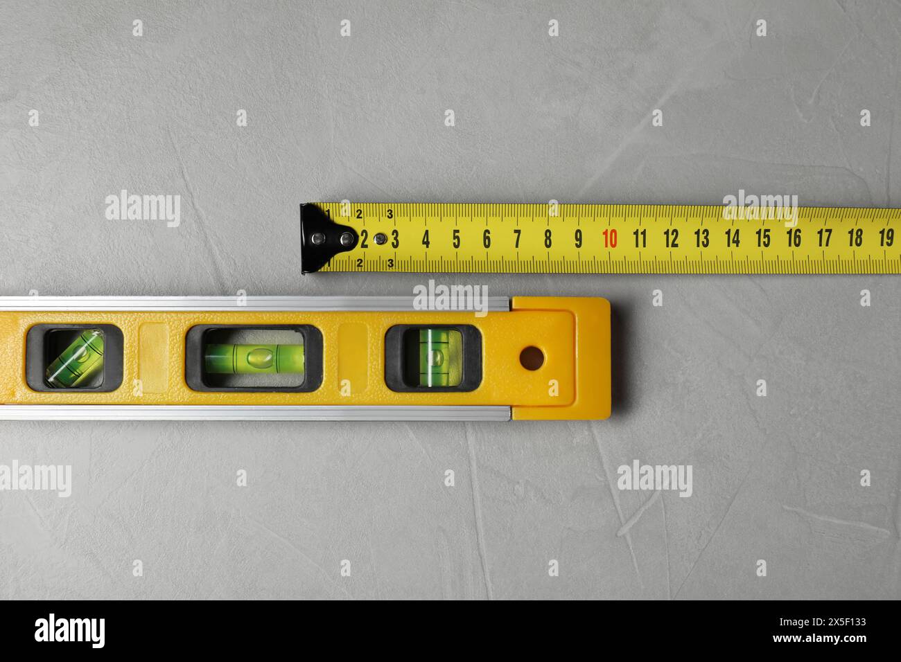 Building level and tape measure on grey table, top view Stock Photo - Alamy