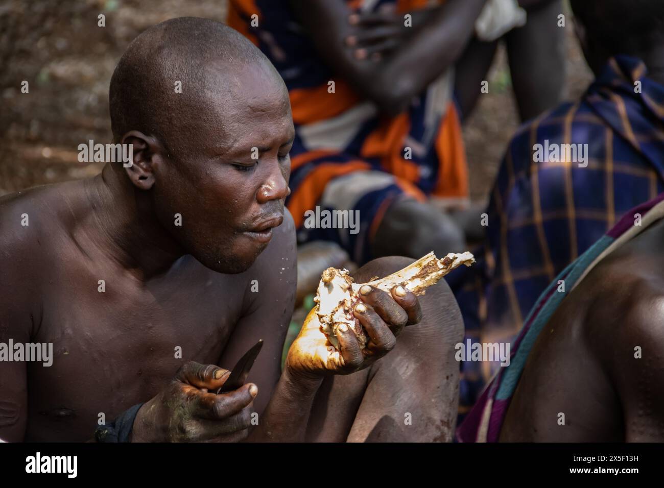 Members of Mursi Tribe in Ethiopia, in Omo valley, gathered around fire ...