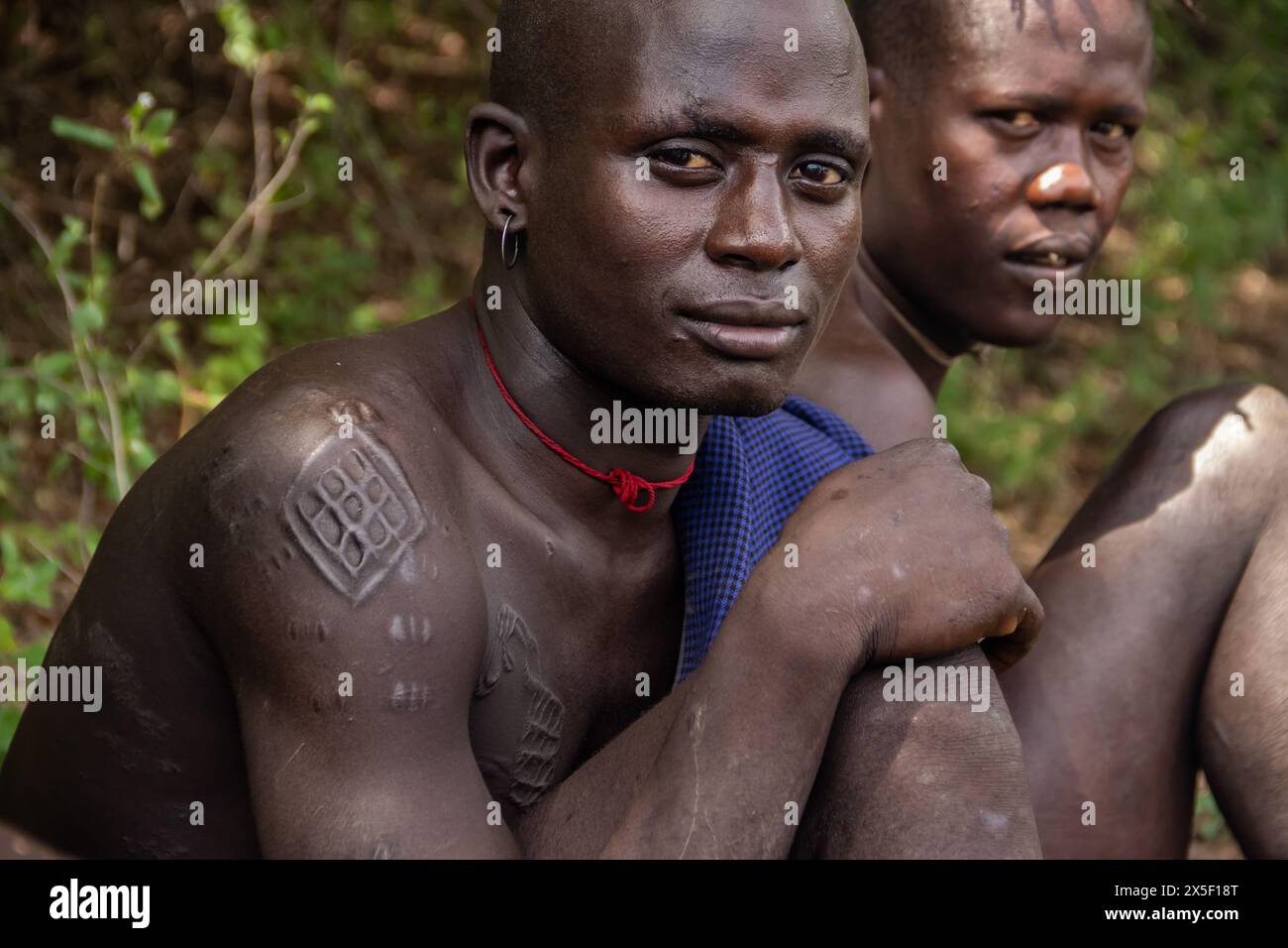Members of Mursi Tribe in Ethiopia, in Omo valley, gathered around fire ...