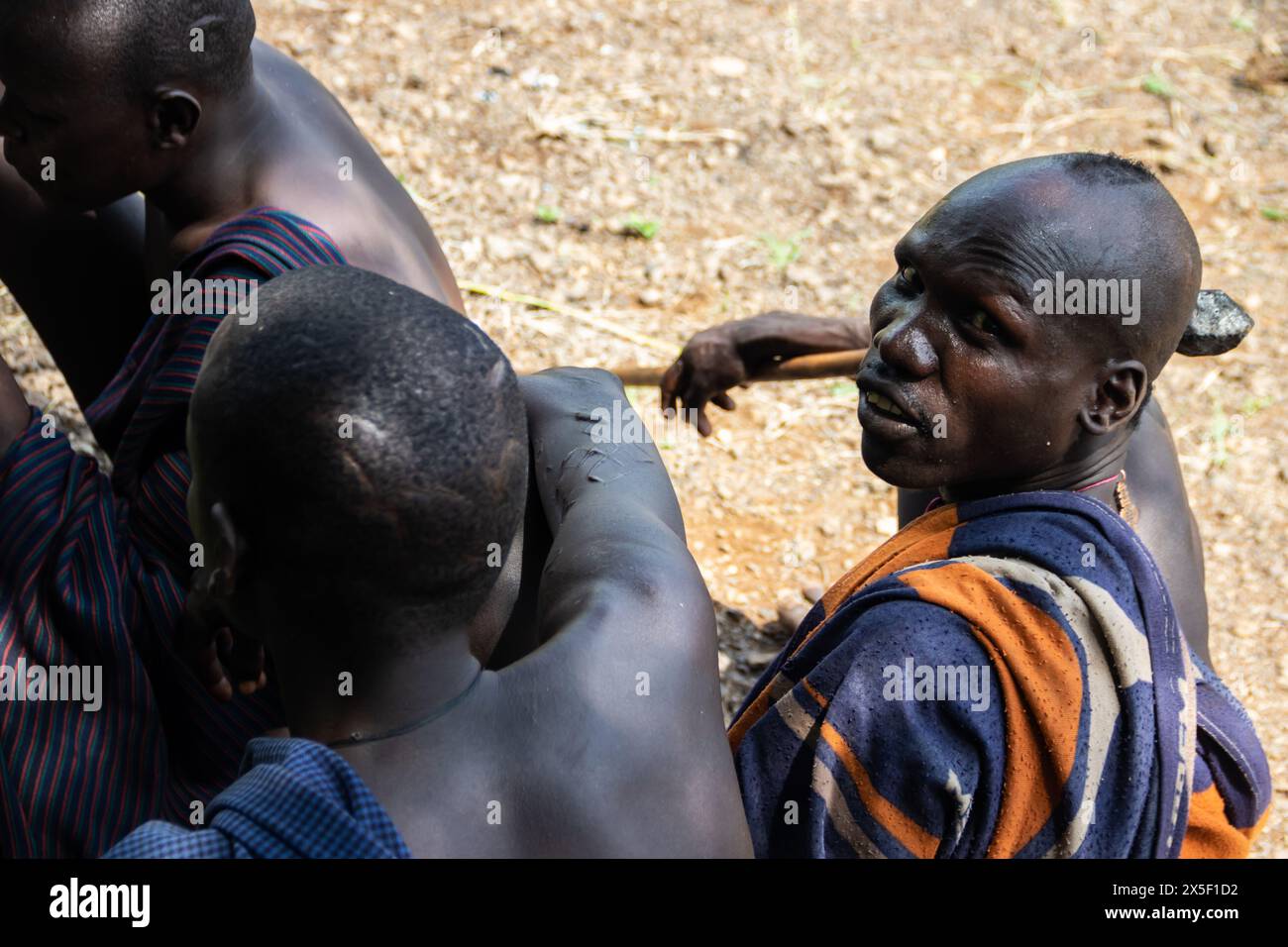 Members of Mursi Tribe in Ethiopia, in Omo valley, gathered around fire ...