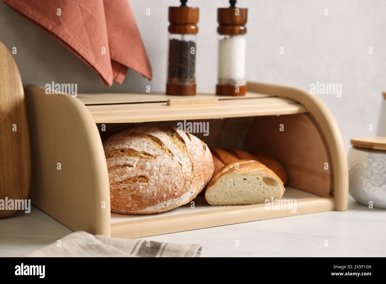 Wooden bread basket with freshly baked loaves on white marble table in ...