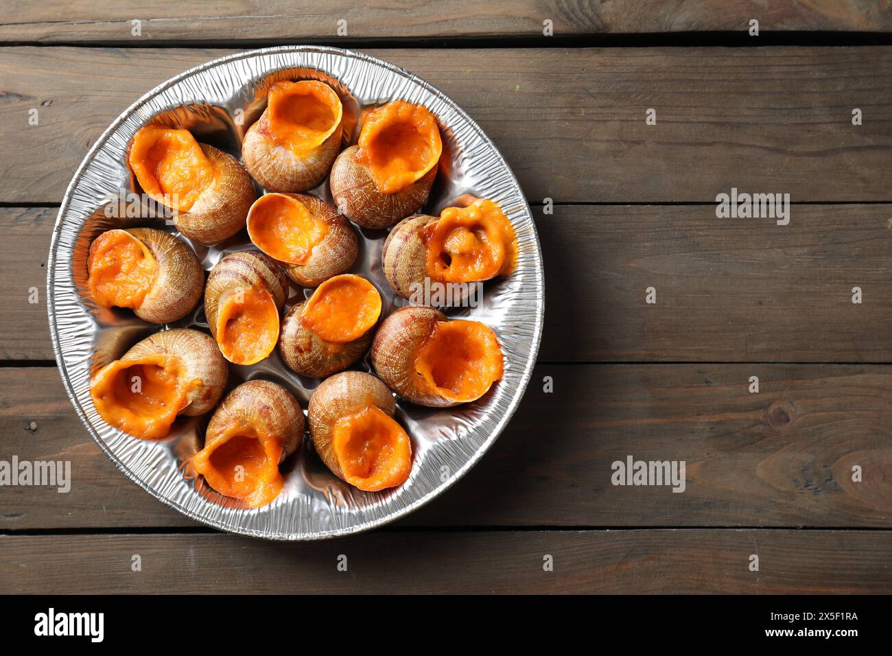 Delicious cooked snails on wooden table, top view. Space for text Stock ...