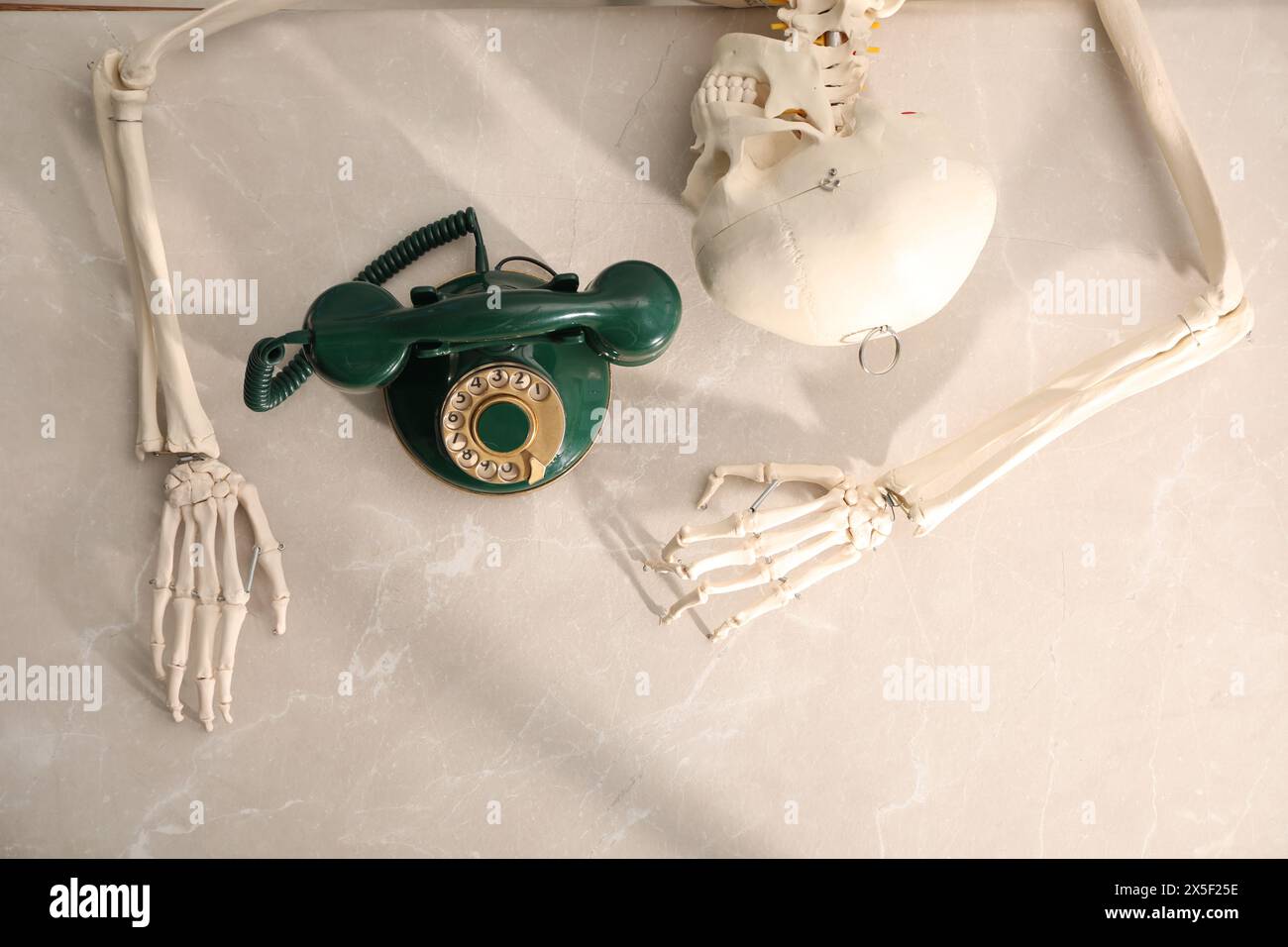 Waiting concept. Human skeleton at grey marble table with corded ...