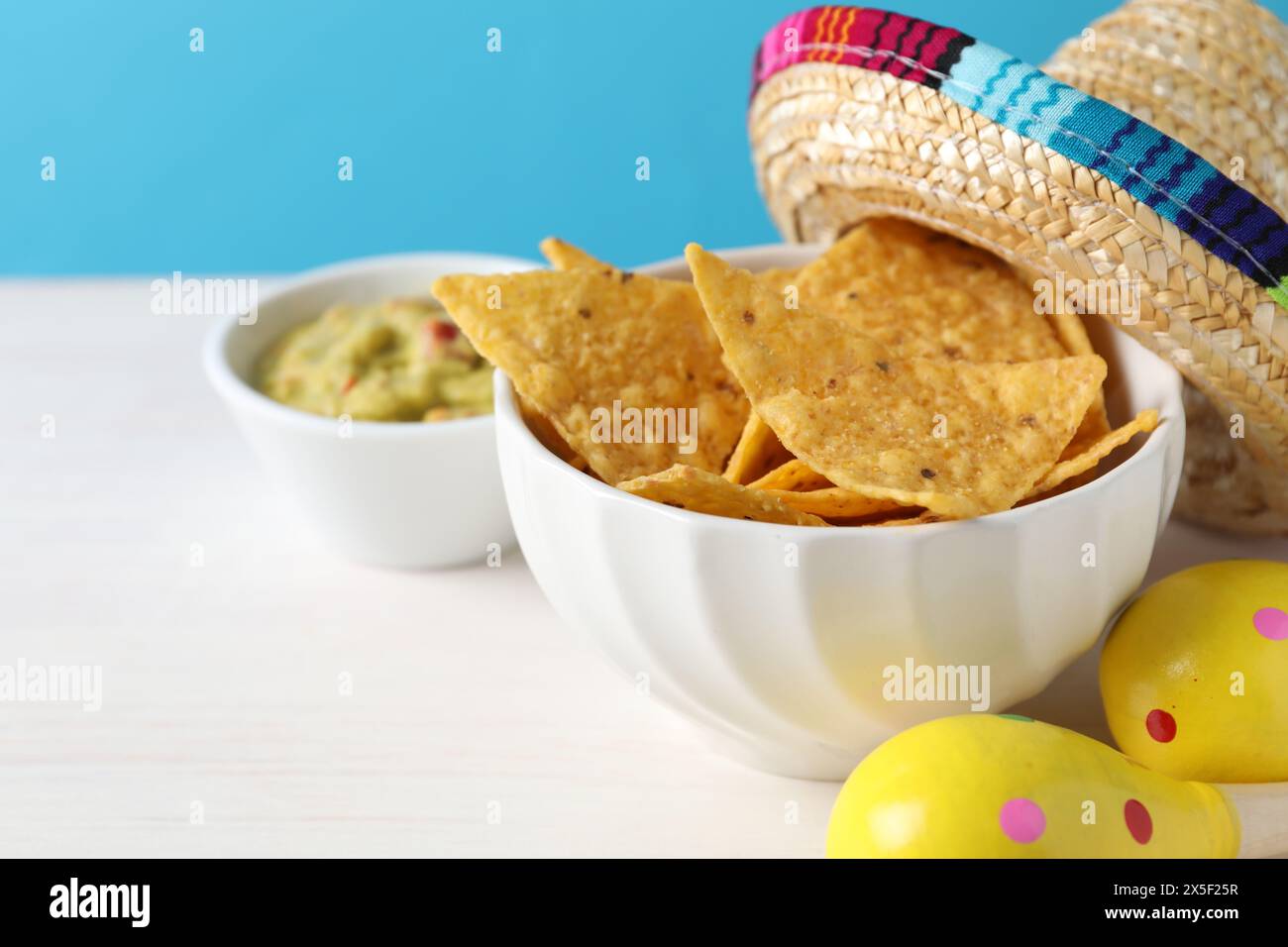 Mexican sombrero hat, nachos chips, guacamole and maracas on white ...