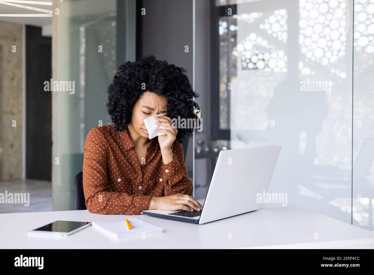A young African American woman feeling emotional, crying at her office ...