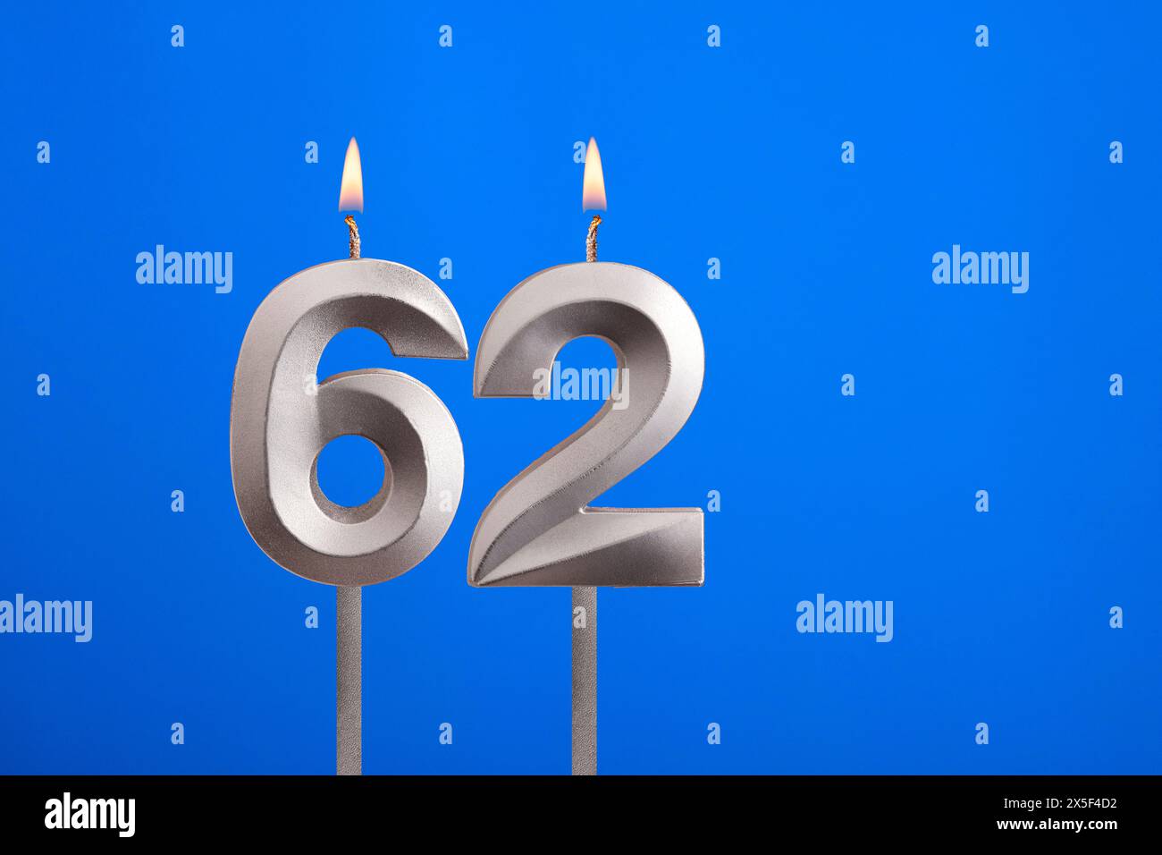 Birthday number 62 - Candle lit on blue background Stock Photo - Alamy