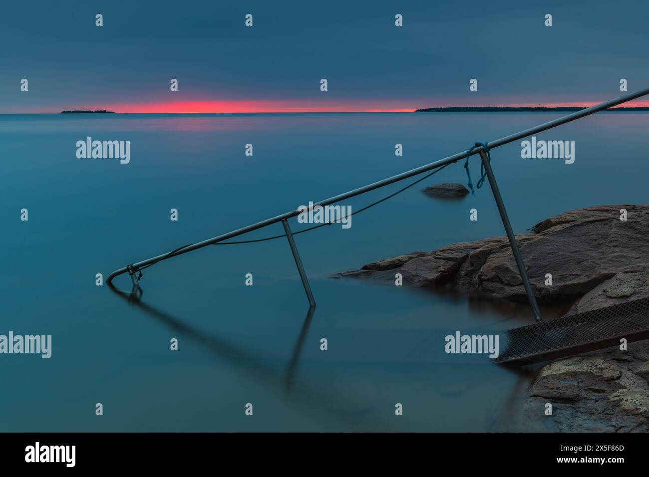 A metal railing is placed on top of a rocky beach, providing a safety ...