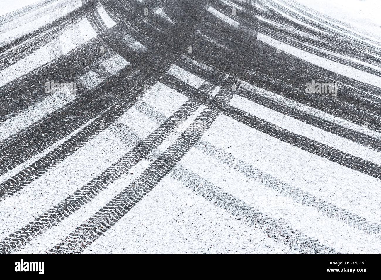 A close-up black and white shot of a tire track on a snowy road ...