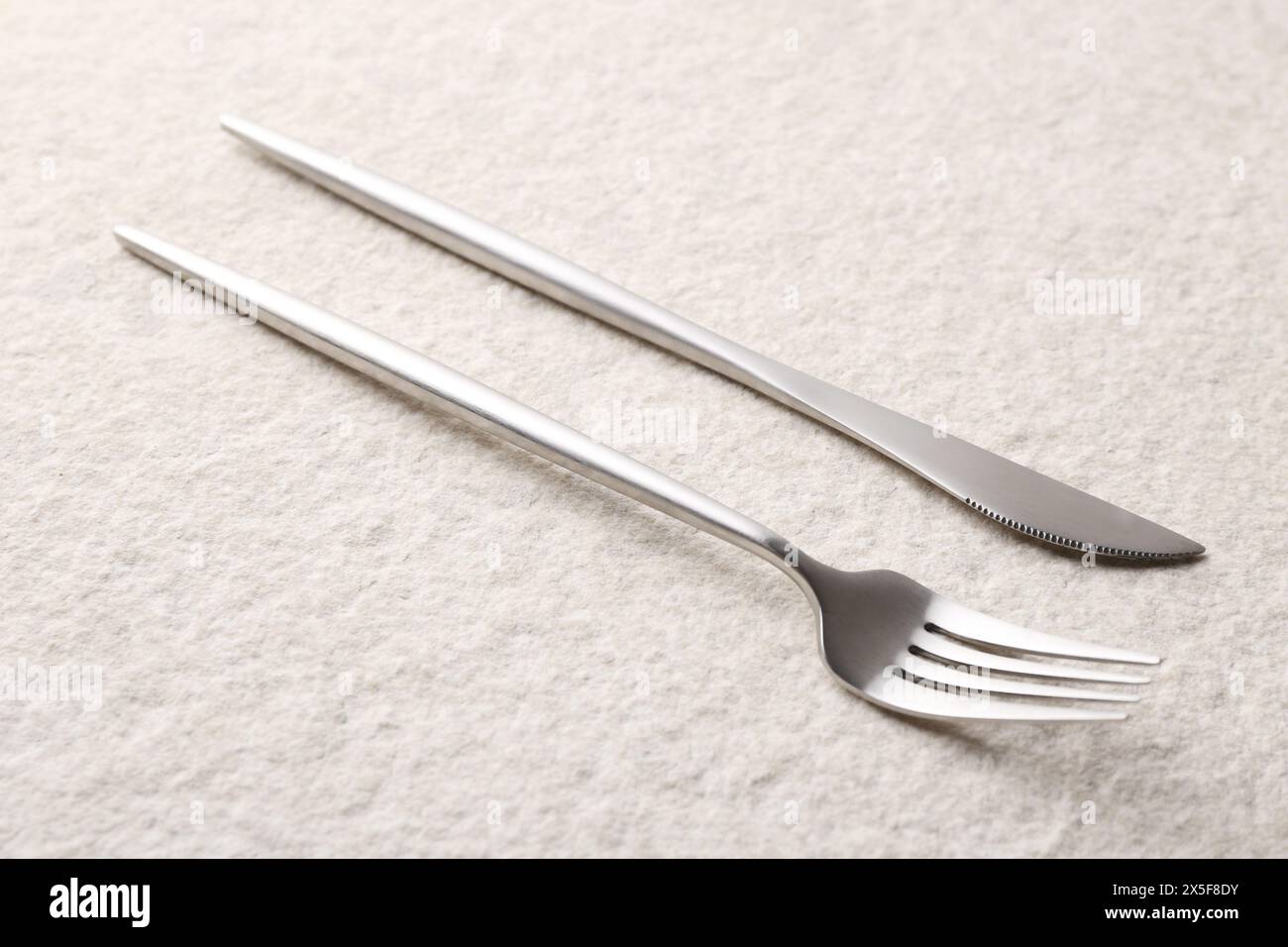 Stylish cutlery. Silver knife and fork on light textured table Stock ...
