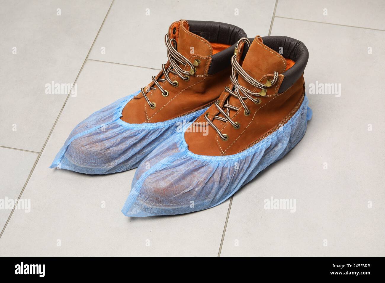 Men`s boots in blue shoe covers on light floor Stock Photo - Alamy