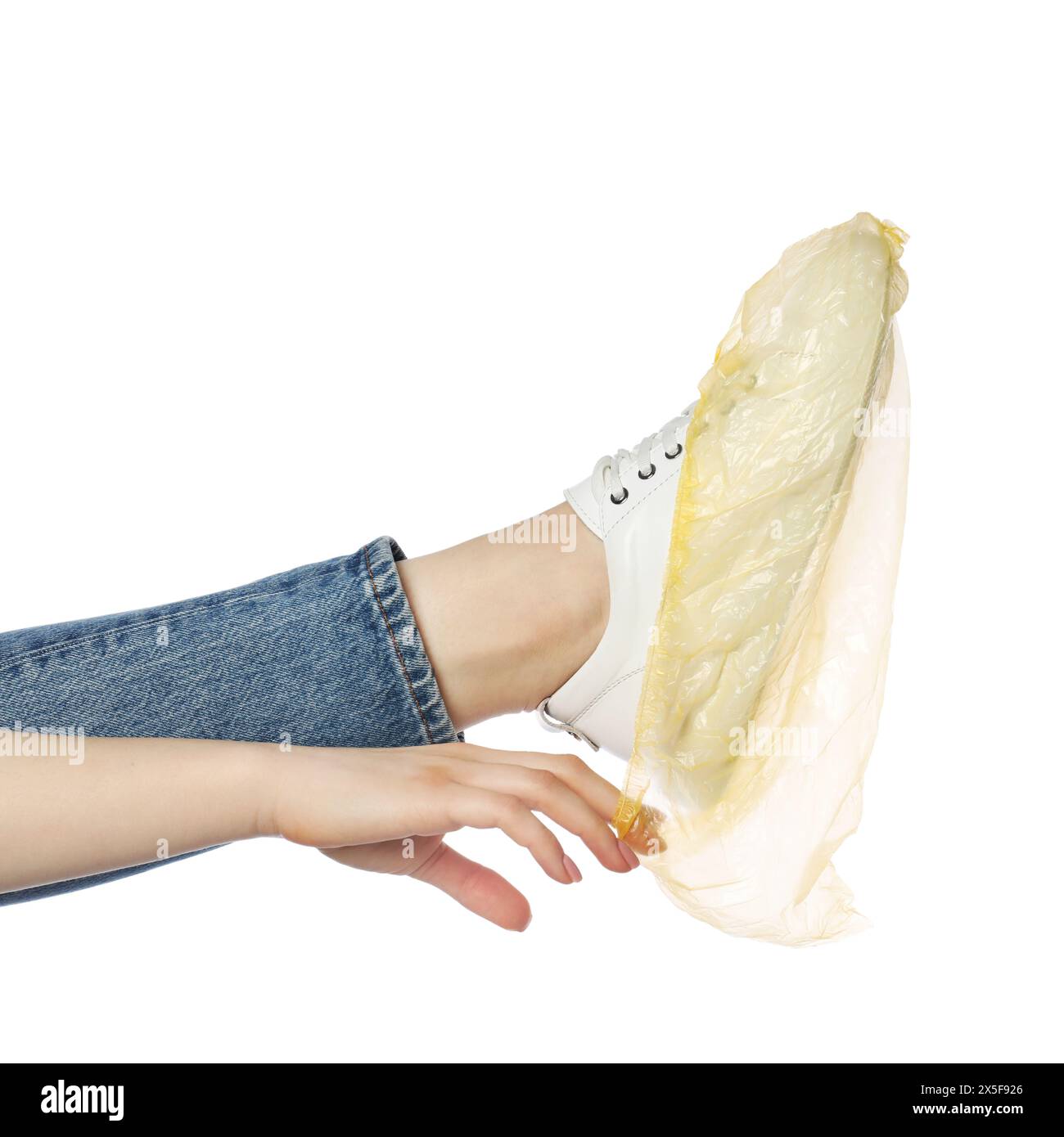 Woman wearing yellow shoe cover onto her sneaker against white ...