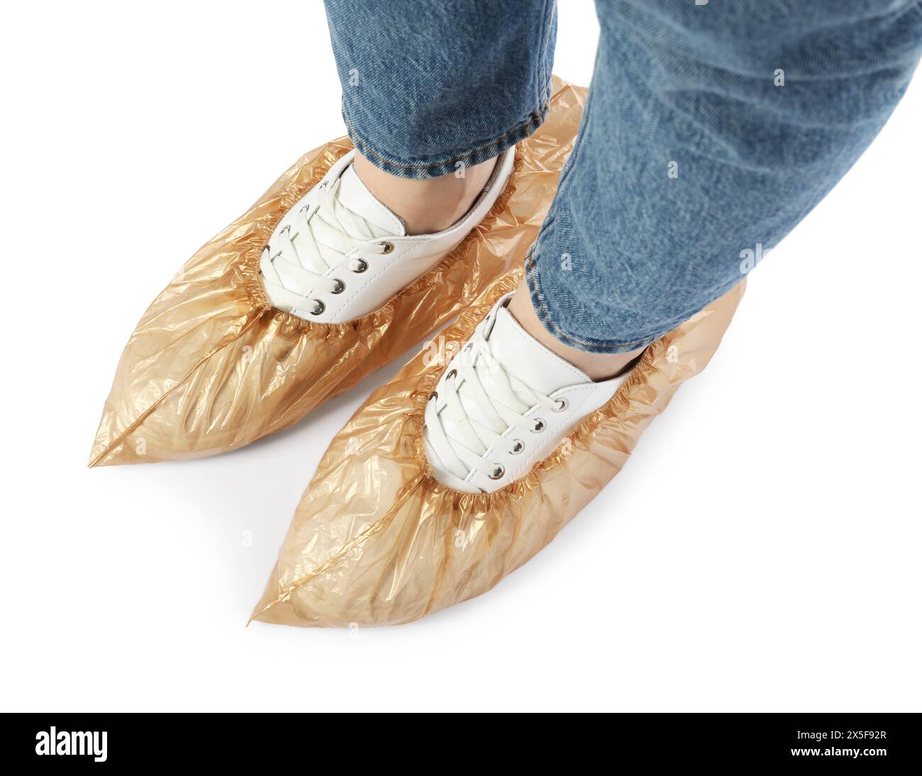 Woman wearing shoe covers onto her sneakers against white background ...