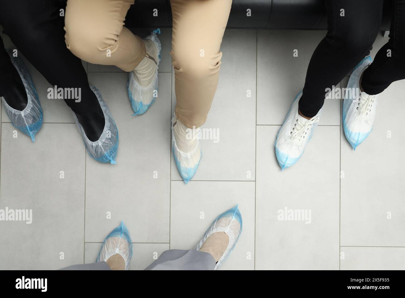Women wearing blue shoe covers onto different footwear indoors, top ...