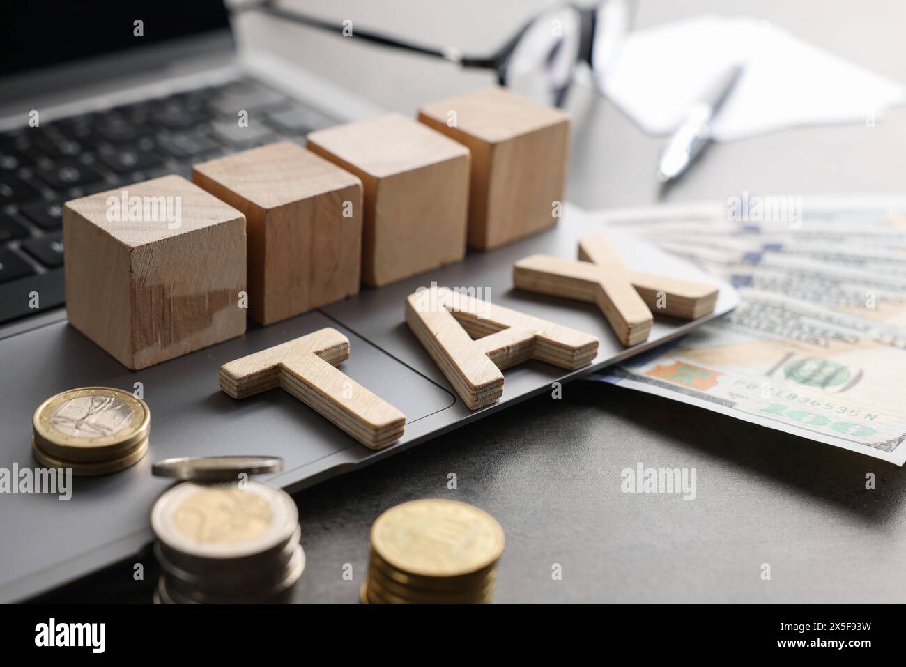 Word Tax made of wooden letters, cubes, laptop, banknotes and coins on ...