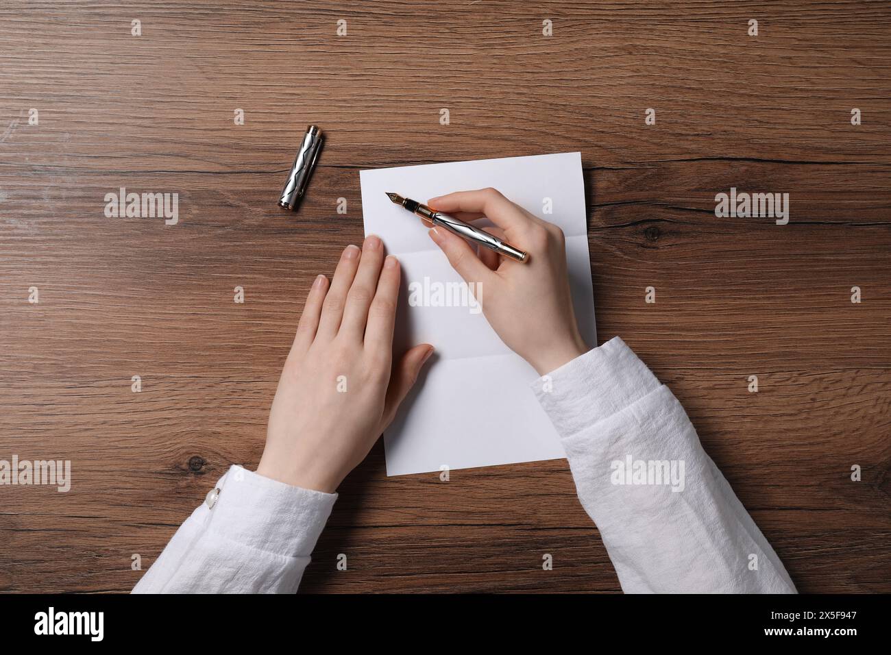Woman writing letter at wooden table, top view Stock Photo - Alamy