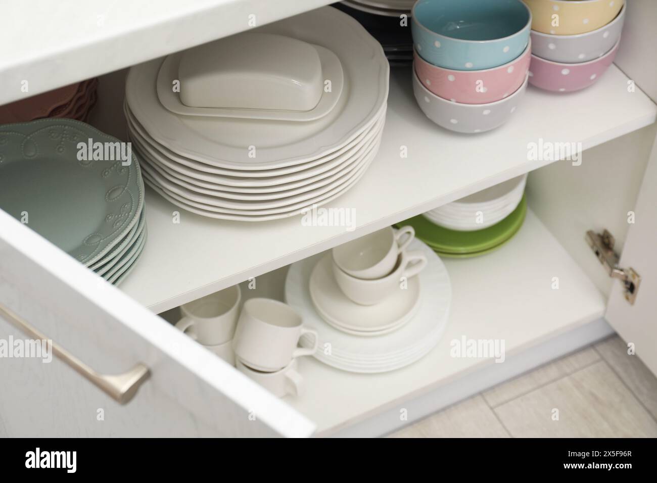 Clean plates, bowls and cups on shelves in cabinet indoors Stock Photo ...