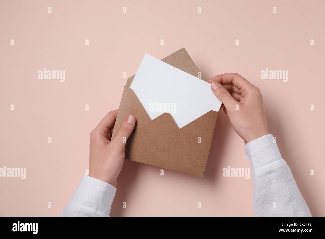 Woman taking card out of letter envelope at beige table, top view Stock ...