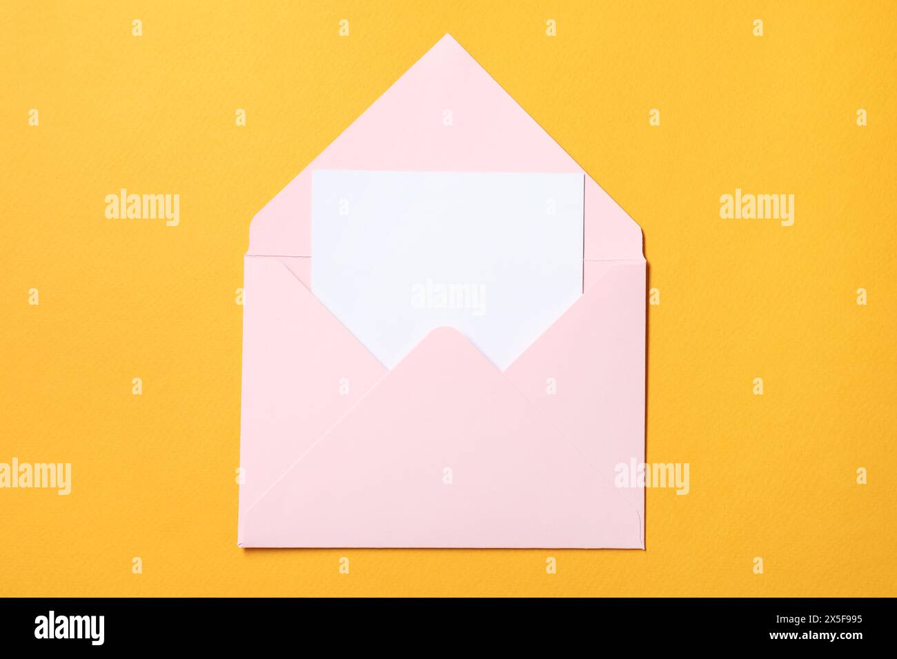 Blank sheet of paper in open letter envelope on orange background, top ...
