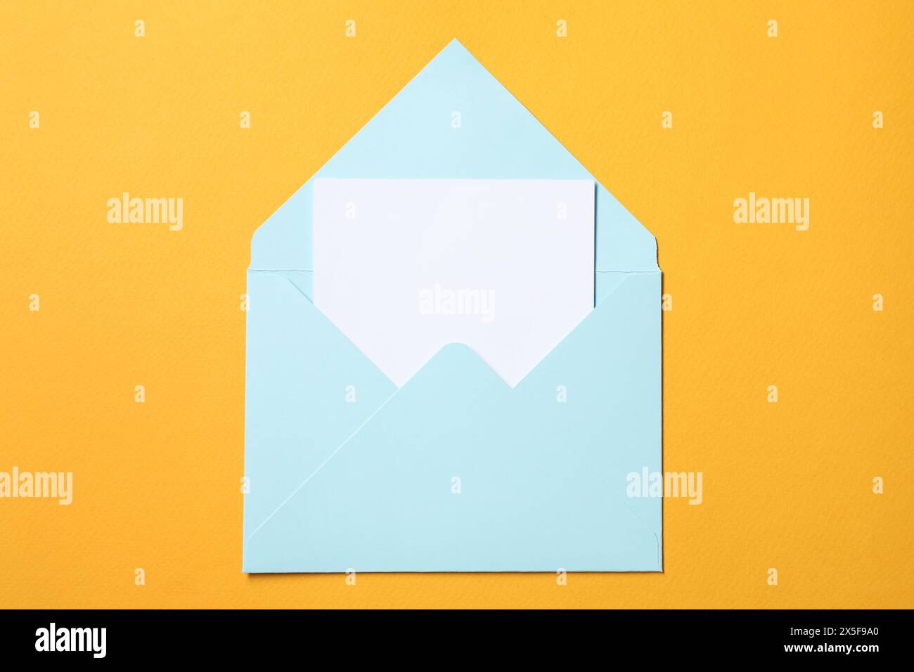 Blank sheet of paper in open letter envelope on orange background, top ...